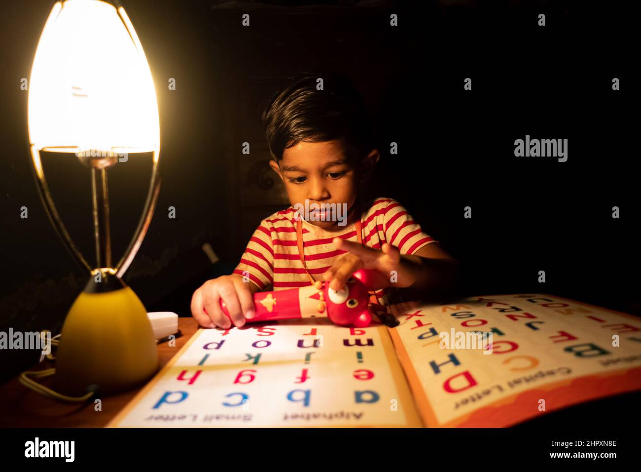 A boy learning the English alphabet using a charger lamp In the evening ...
