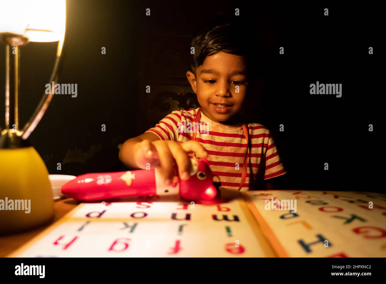 A boy learning the English alphabet using a charger lamp In the evening ...