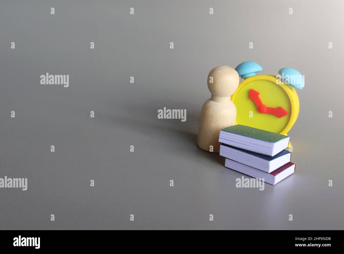 Wooden doll, stack of books and alarm clock. Copy space for text ...