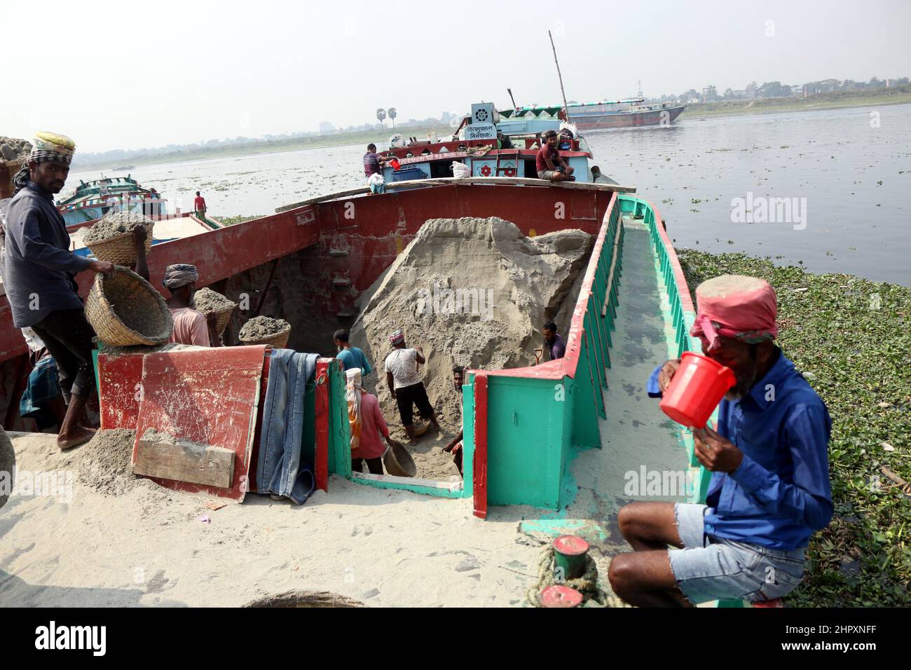 Labor load-unloading work on the banks of polluted river Shitalakshya ...