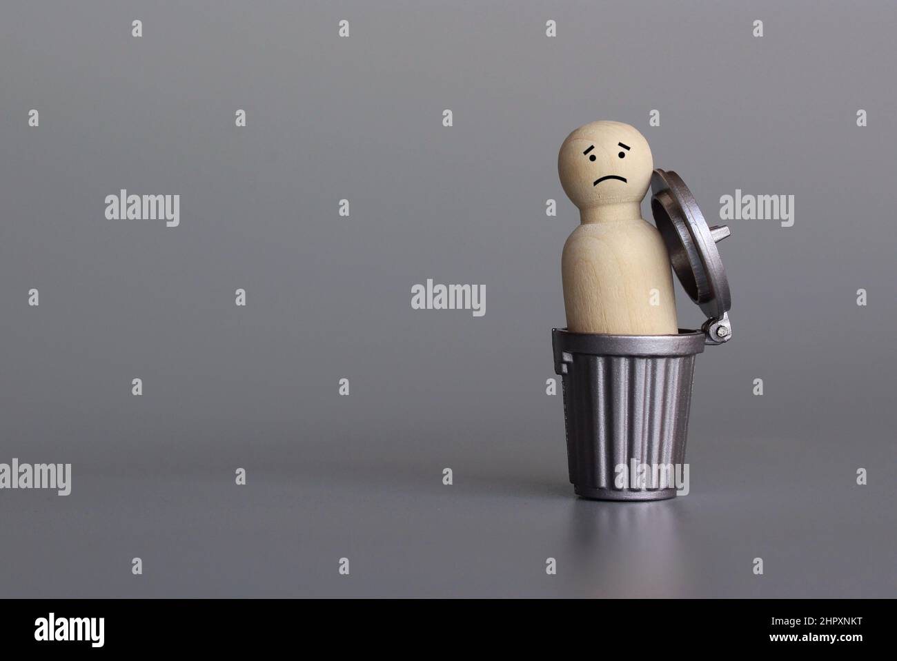 Wooden doll inside trash can. Down in the dumps, depressed, sad and ...