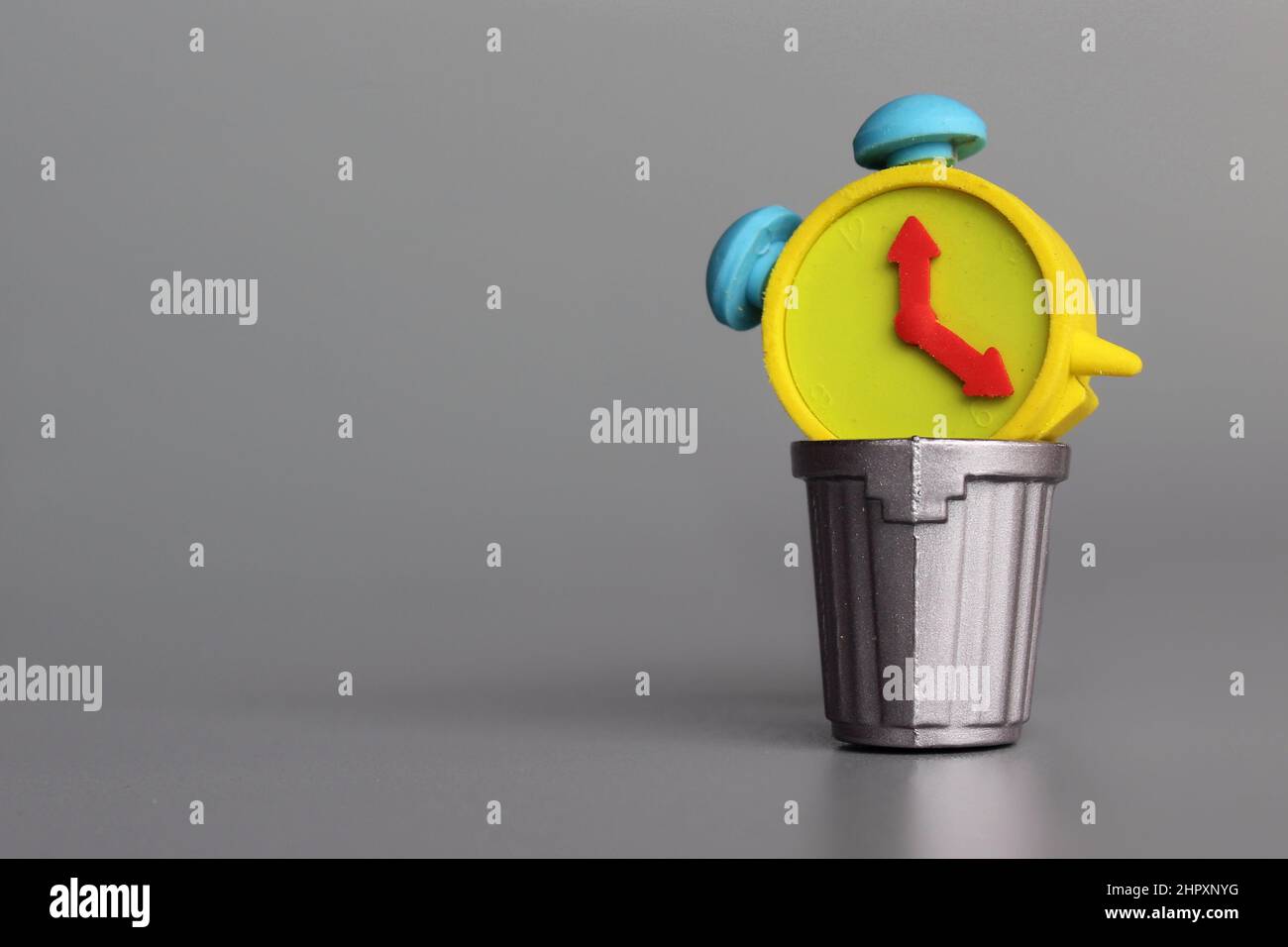 Wasting time concept. Alarm clock inside garbage can. Copy space for ...