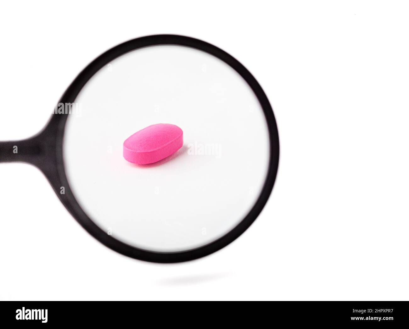 Zooming magenta pill using magnifying glass isolated on white ...