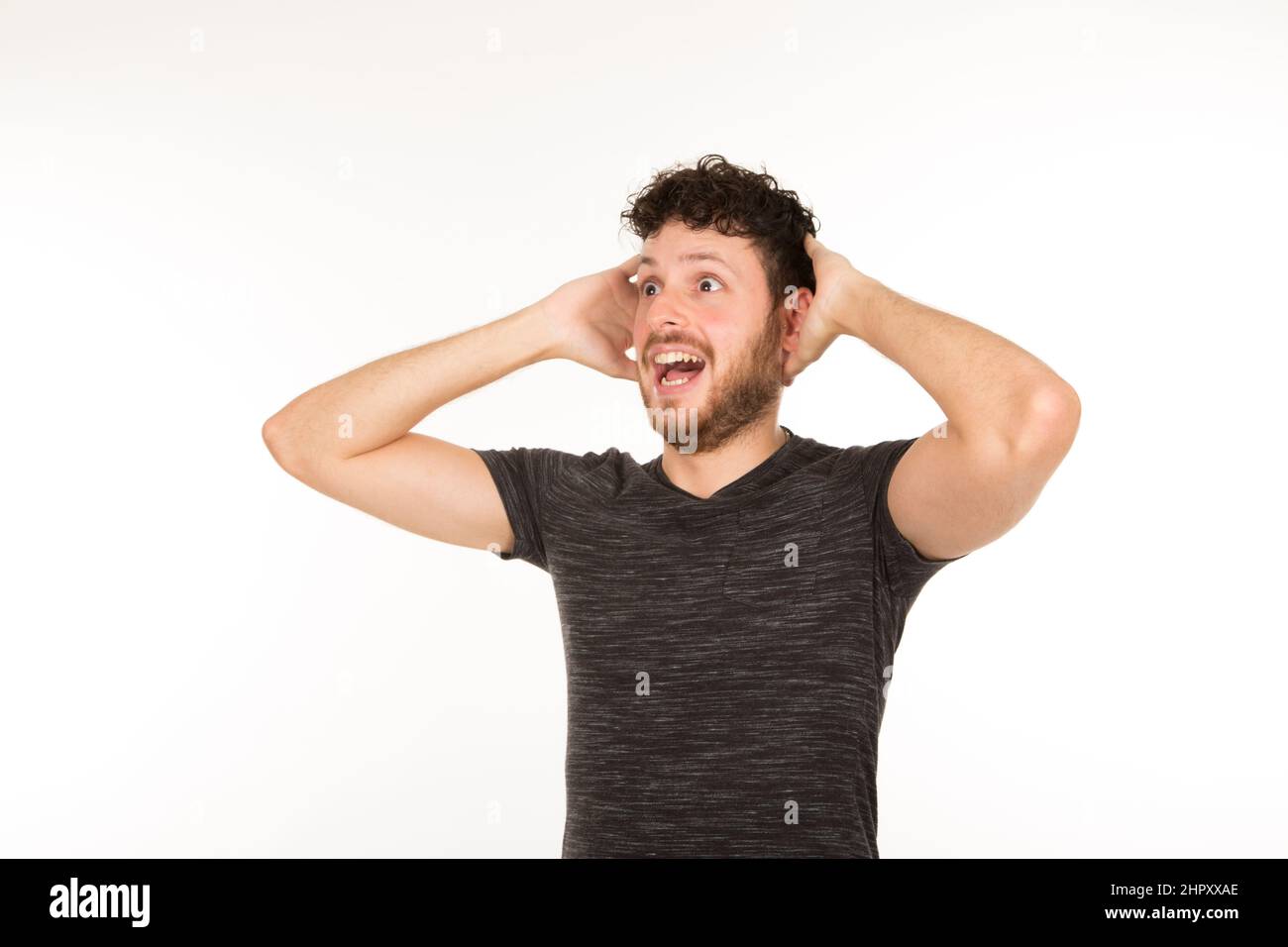 young bearded man shouting with his hands on his head on a white ...