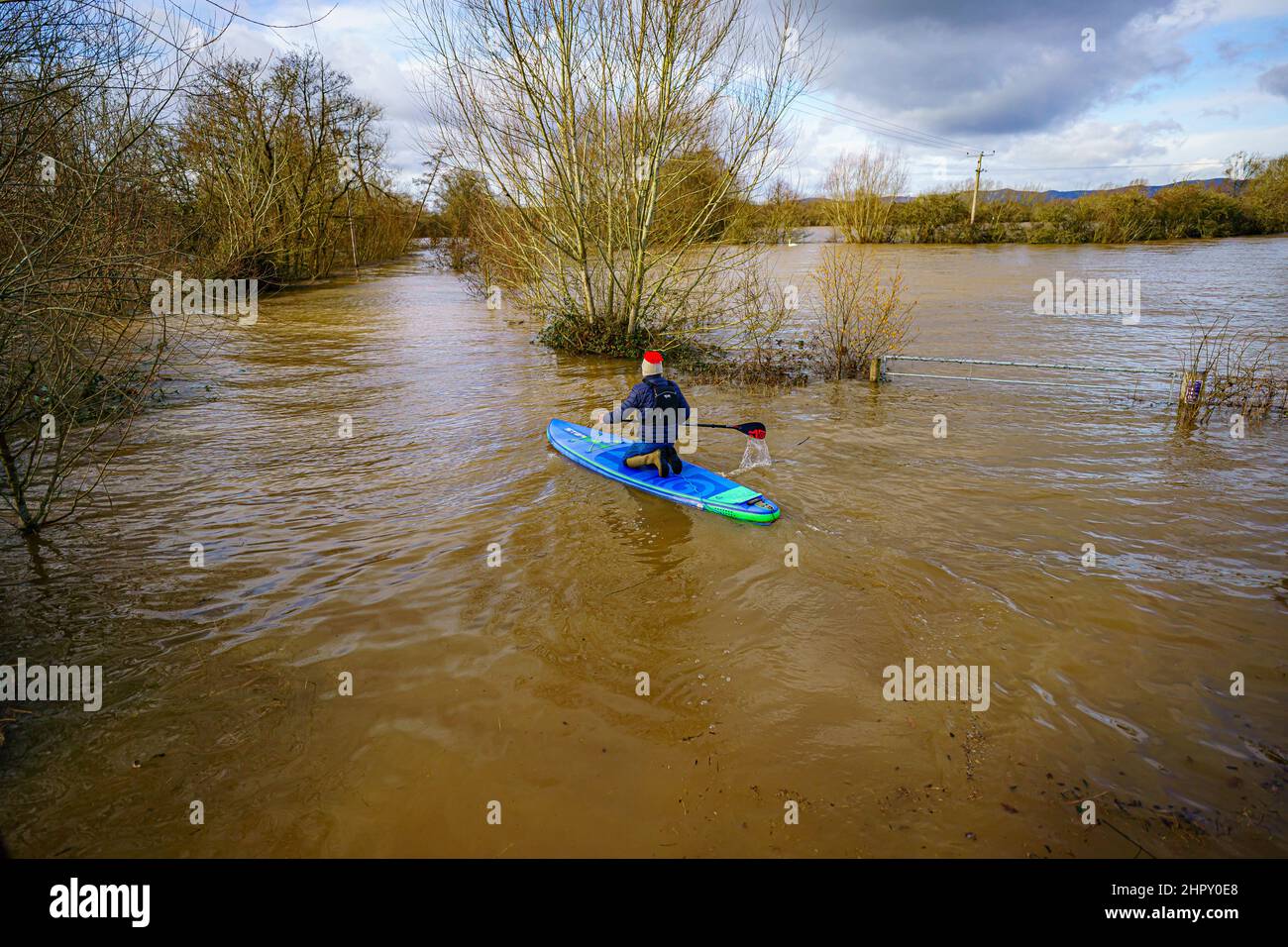 A man on a paddleboard makes his way along the flooded Ferry Lane at ...