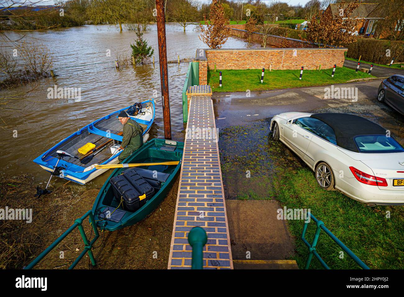 People use boats to cross the flooded Ferry Lane and reach the flood ...