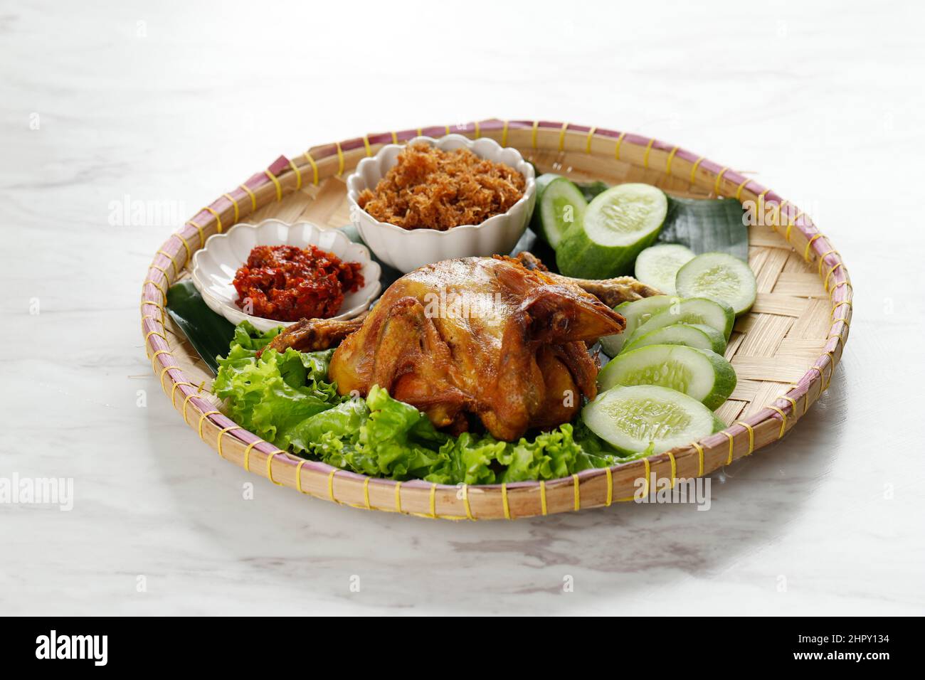Ayam Goreng Bakakak or Whole Fried Chicken, Served with Sambal and Serundeng, on White Table ...