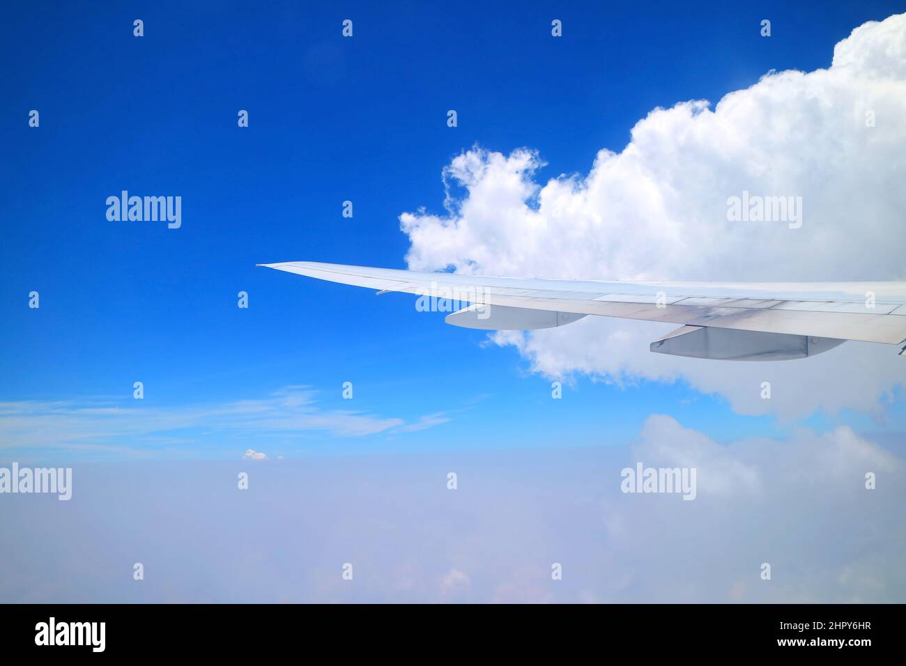 Vivid blue sky and pure white clouds with airplane wing seen from plane ...