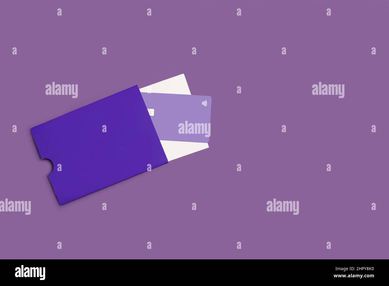 Credit card in a blue packaging on a purple background with copy space ...