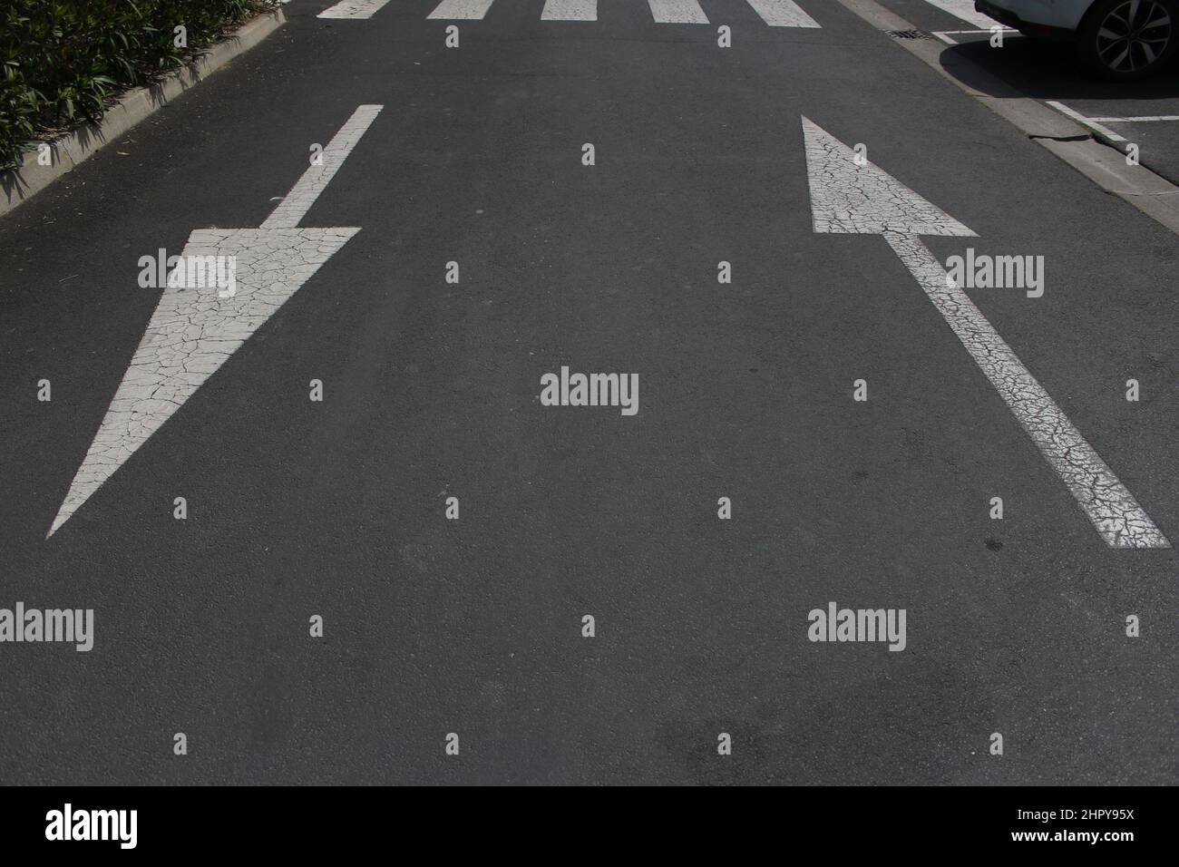 Asphalt road with two arrows in white indicating the direction of ...