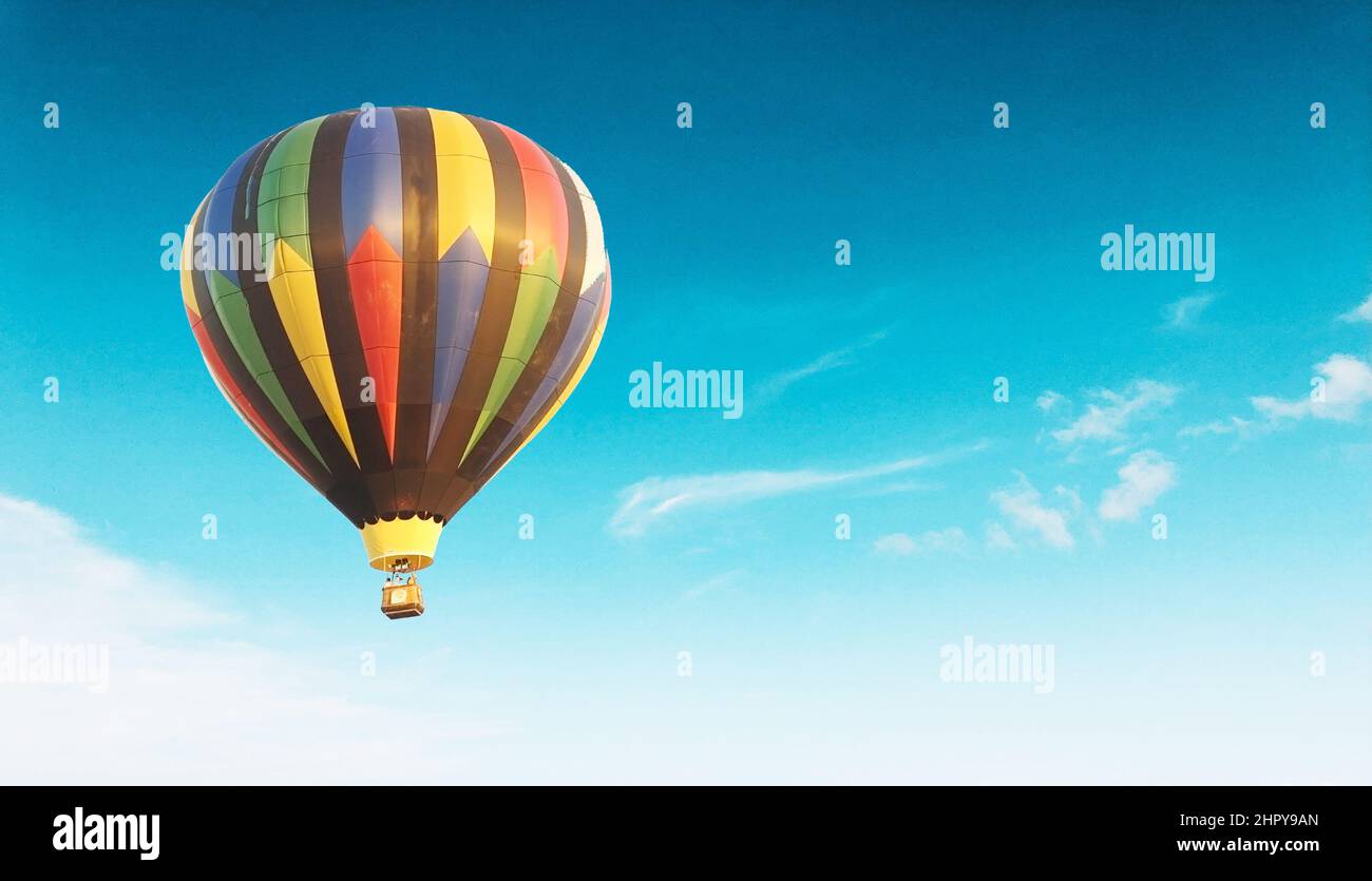Colorful air baloon flying high in the blue sky with clouds floating ...