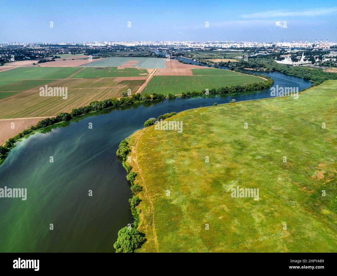 Wide river flowing between fields Stock Photo - Alamy
