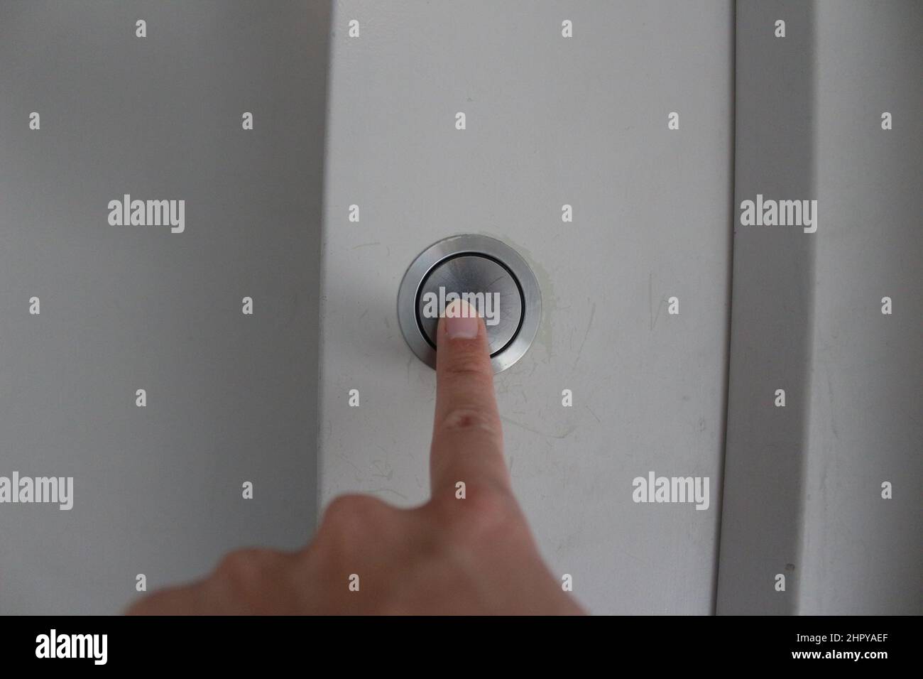 Hand finger pressing the elevator metal button on a white wall Stock ...