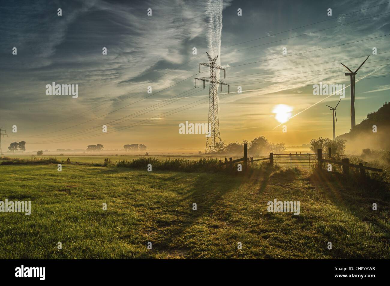 Sunset scenery over the farm with wind turbines and transmission tower ...