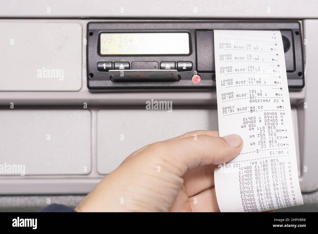 Hand holding a printed time record check coming out of the digital ...