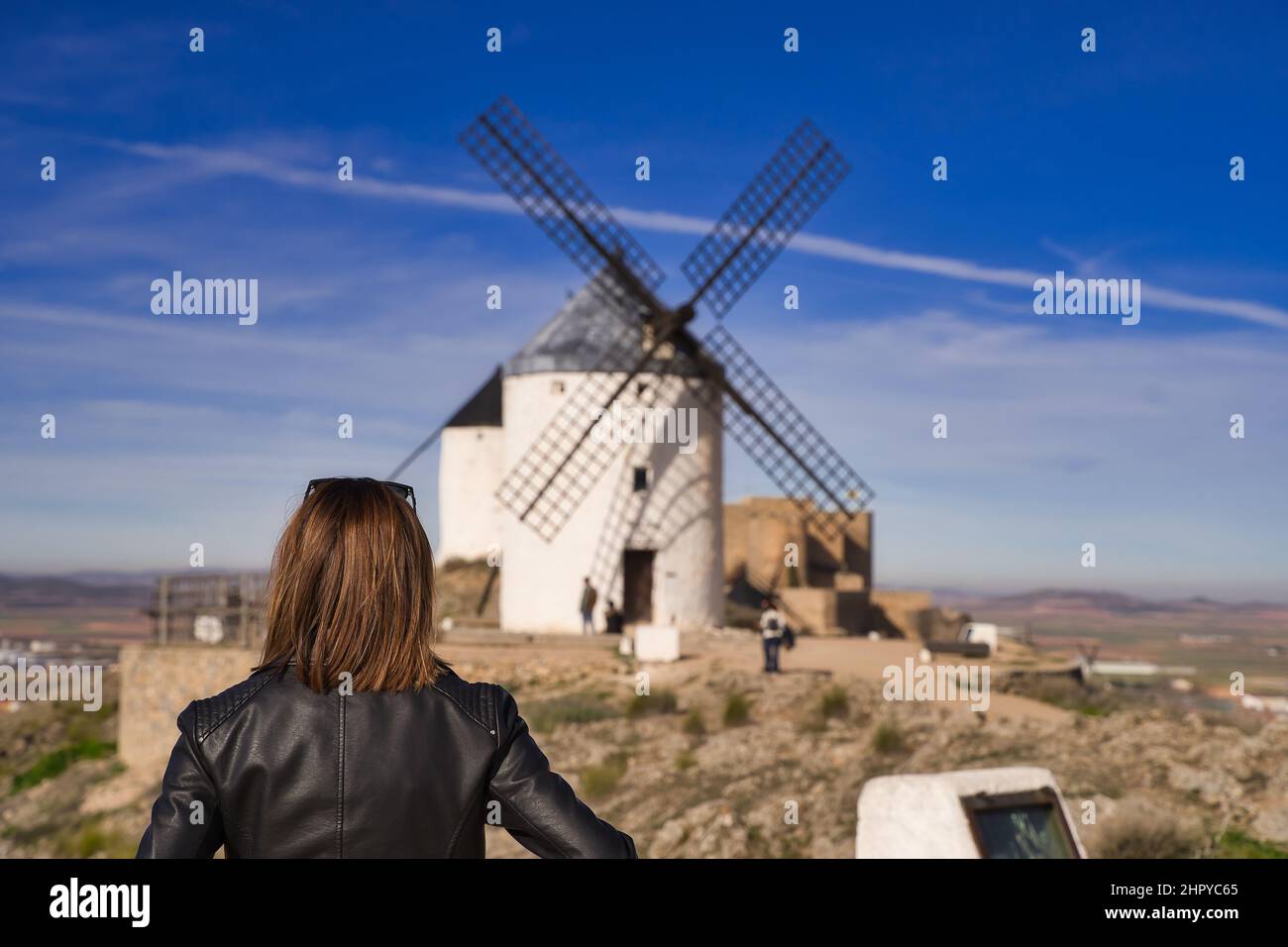 Back view of a woman standing in front of an old historical windmill in ...