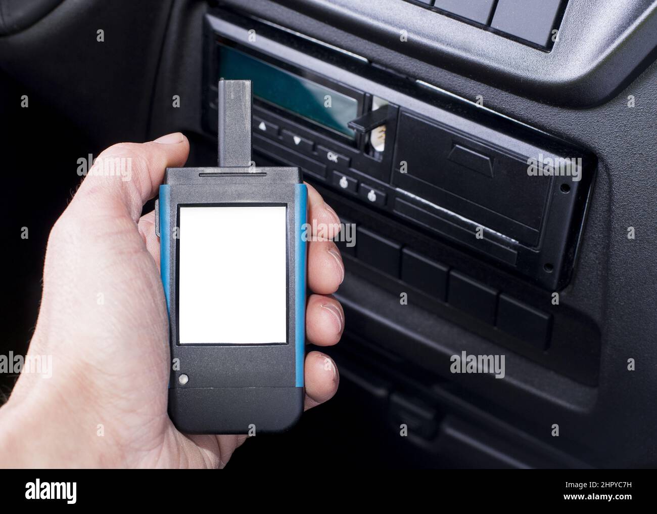 Hand holding a digital tachograph reader with an isolated white screen ...