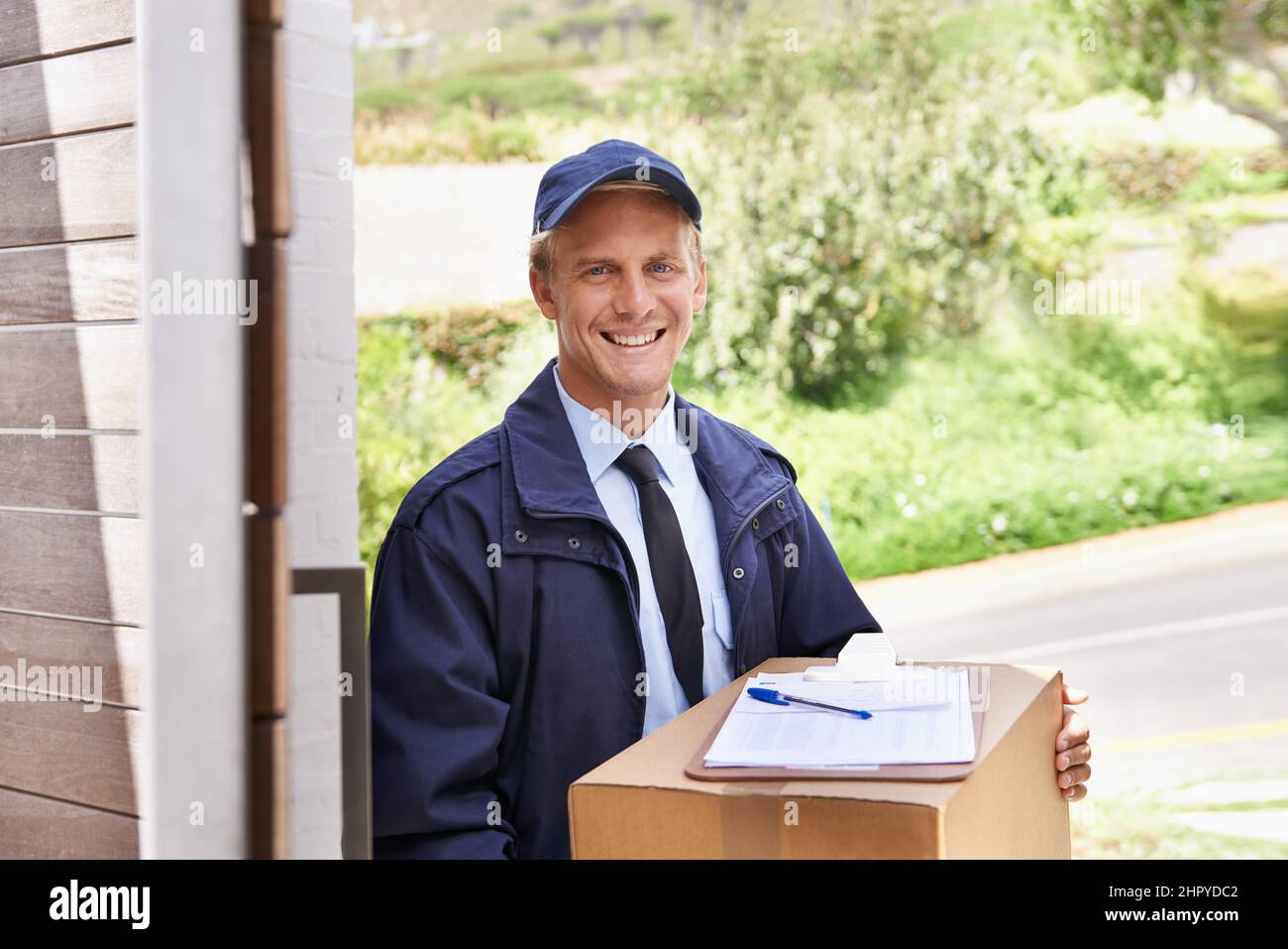 Delivery with a smile. A friendly delivery man delivering a package to ...