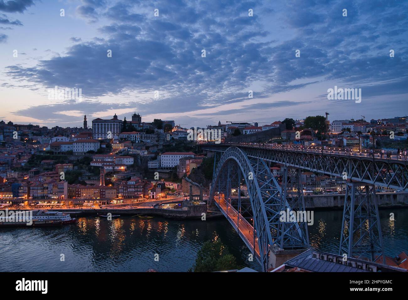 Aerial view of a bridge and illuminated city of Porto under a blue ...