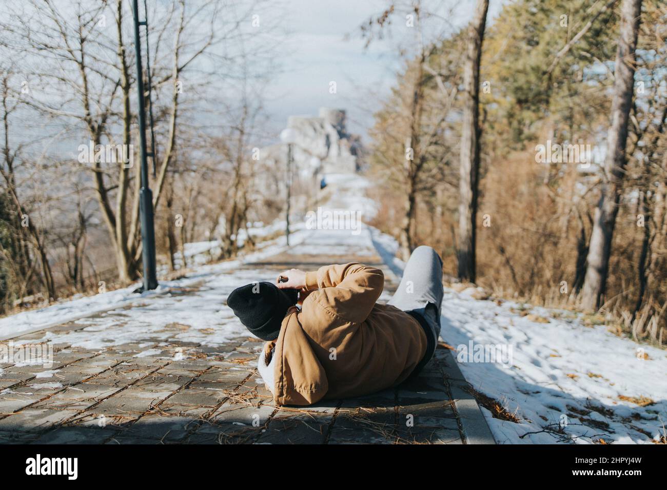 Caucasian (White) photographer lying on the ground in the winter park ...