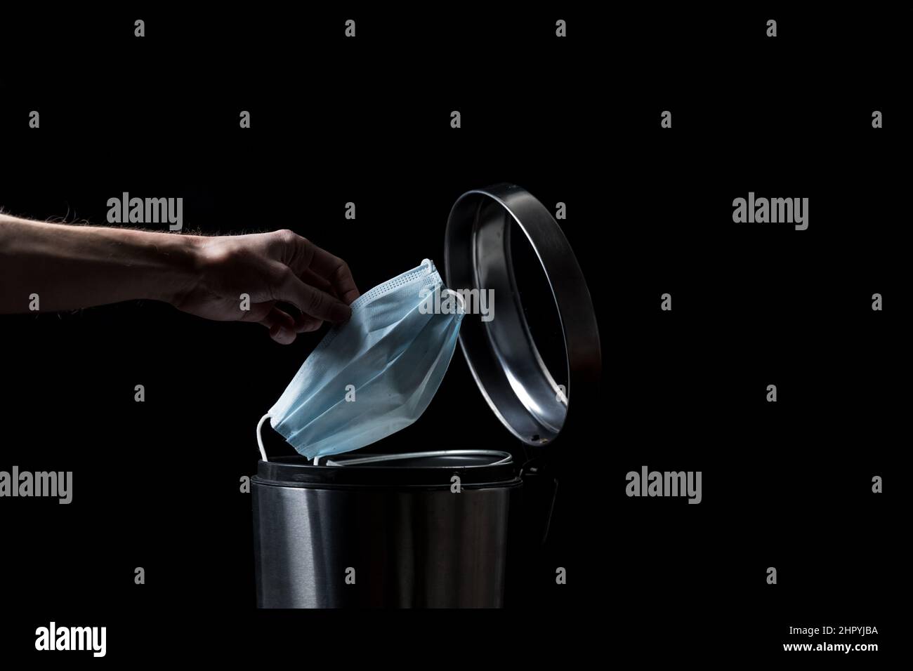 Closeup of a man throwing a used mask in trash bin Stock Photo - Alamy