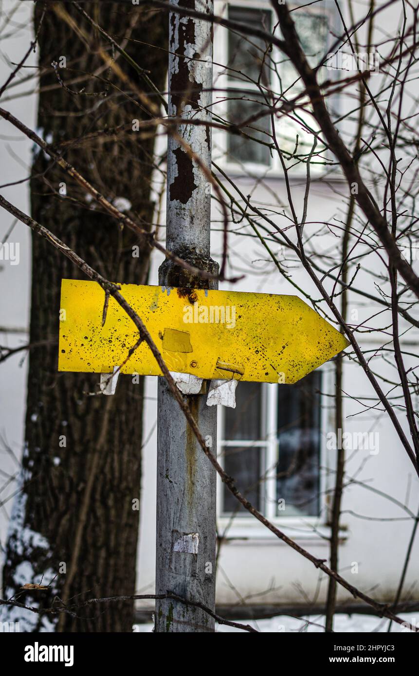 View pf a yellow metal arrow with tree twigs and home wondow in the ...