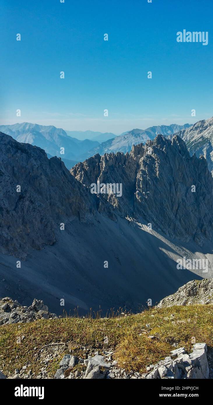 Beautiful vertical view with rocky mountains, grassland and blue sky on ...
