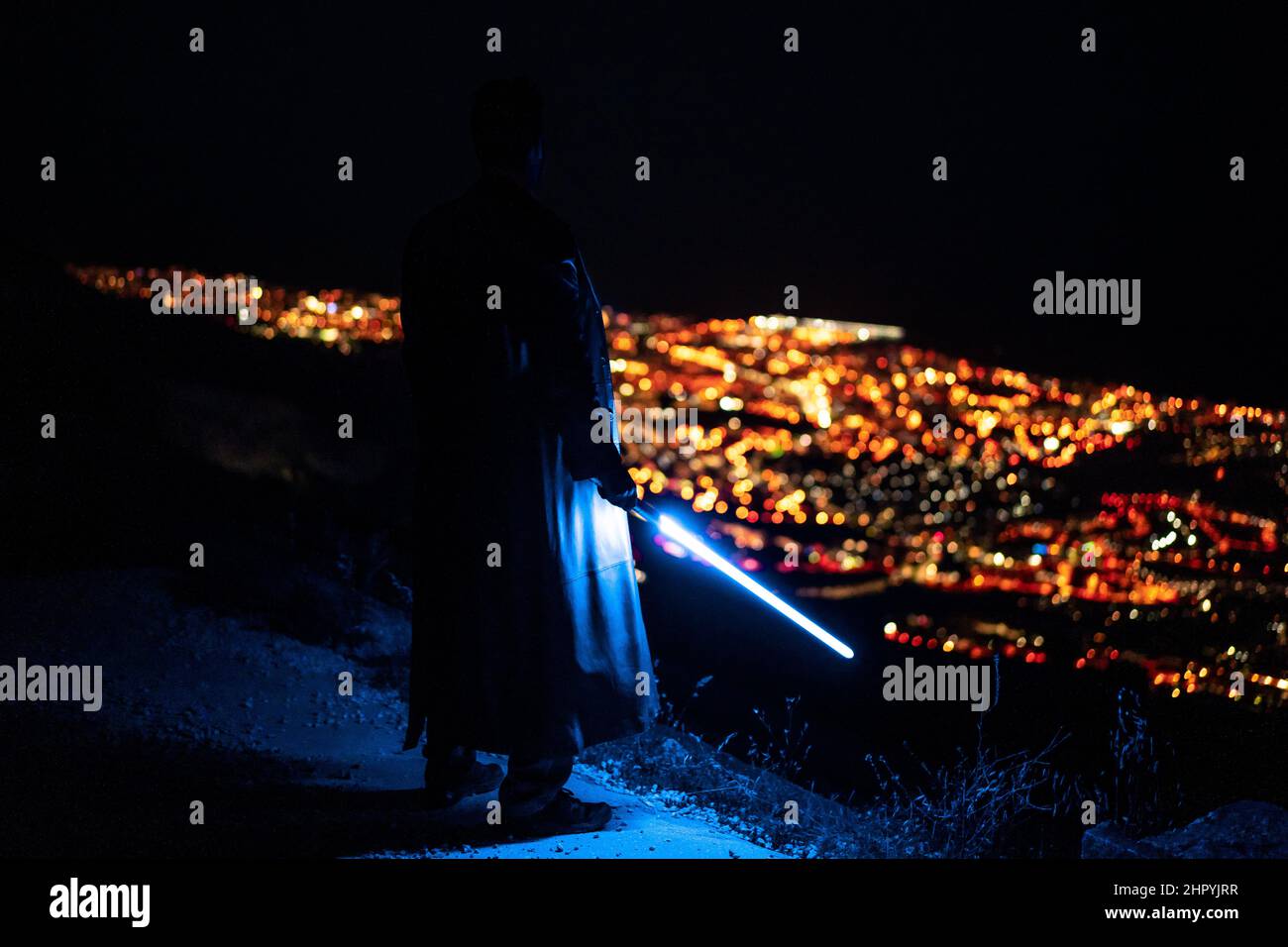 Man wearing a leather coat and holding a neon sword Stock Photo - Alamy