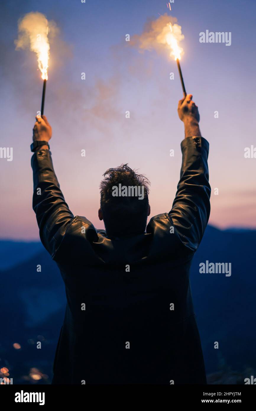 Man wearing a leather coat and holding two firework sticks Stock Photo ...