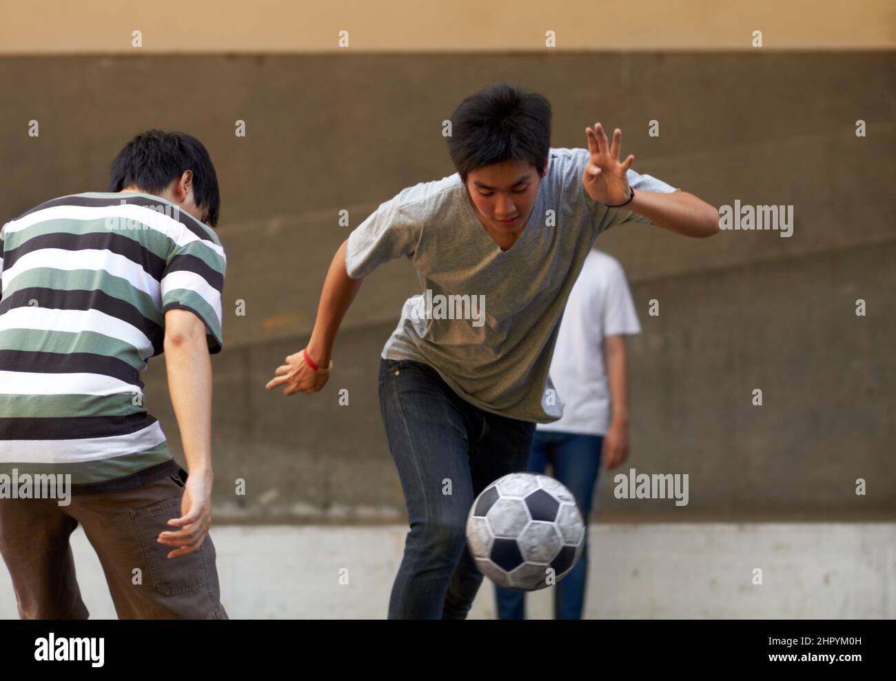 Dribbling to the goal. Young asian males playing soccer outside Stock ...