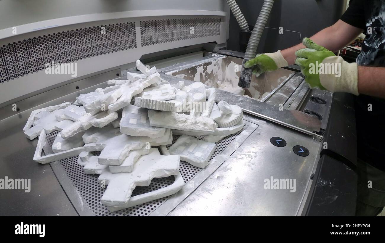 Man cleans details printed on industrial 3D printer from white plastic ...