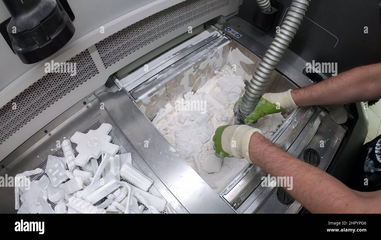 Man cleans details printed on industrial 3D printer from white plastic ...