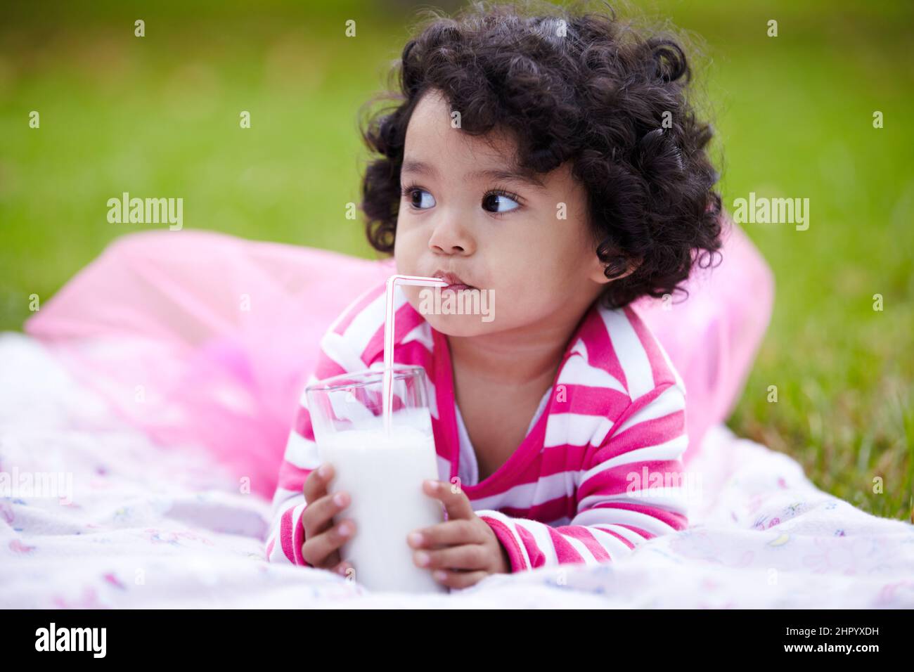 Mmmmm. Adorable little girl drinking milk through a straw while lying ...