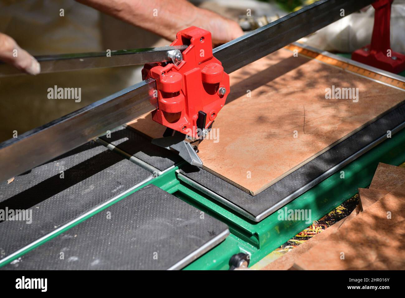 The mason cuts the tile by hand using a cutter Stock Photo - Alamy