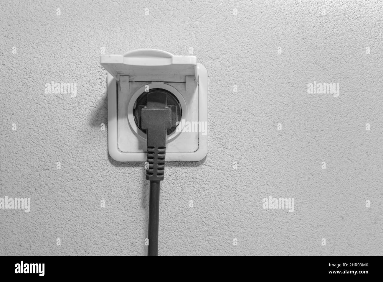 Black plug cable wire stuck into the electricity outlet of home power ...