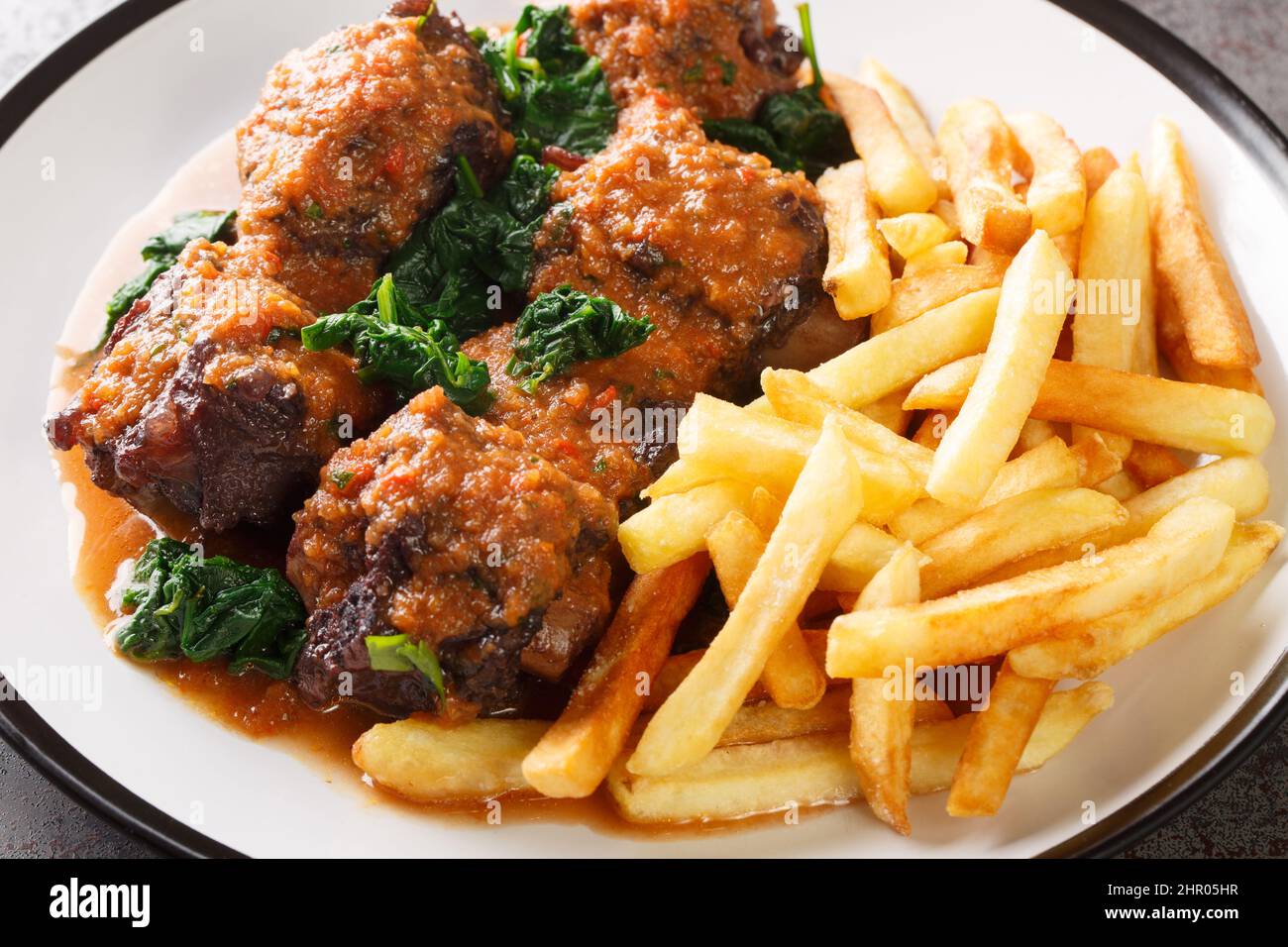 Meat for bull tail stew Rabo de toro served with french fries on white ...