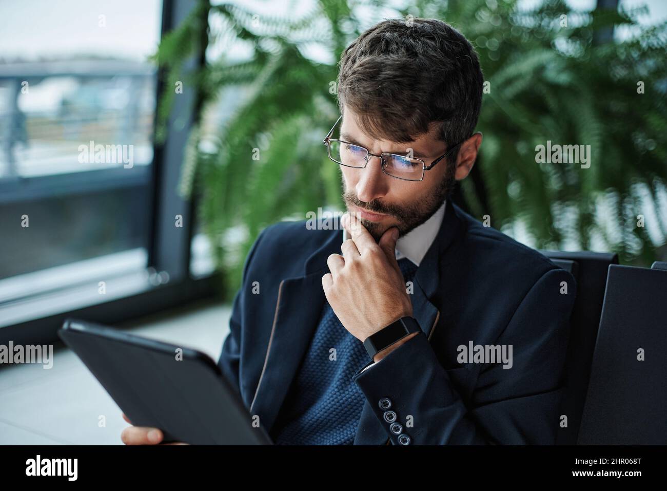 business man thoughtfully looking at the screen of a digital tab Stock ...