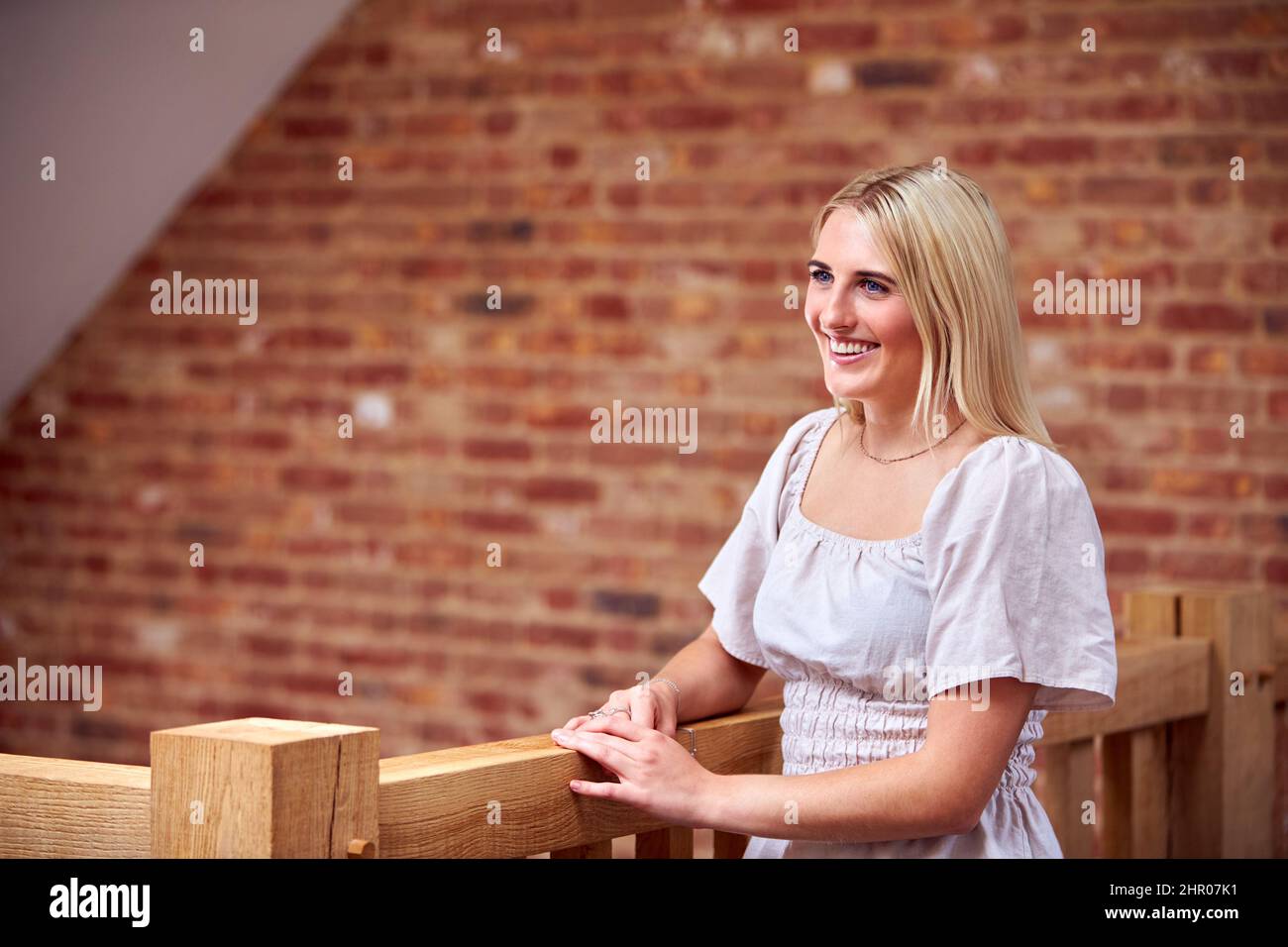Young Woman Standing By Wooden Staircase At Home Talking And Laughing ...
