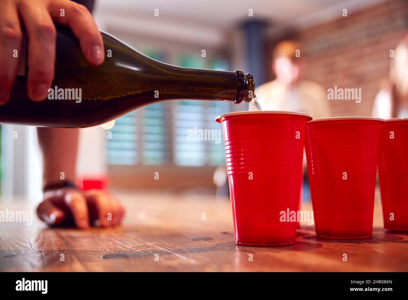 Close Up Of Man Pouring Wine Into Plastic Cups For Friends At House ...