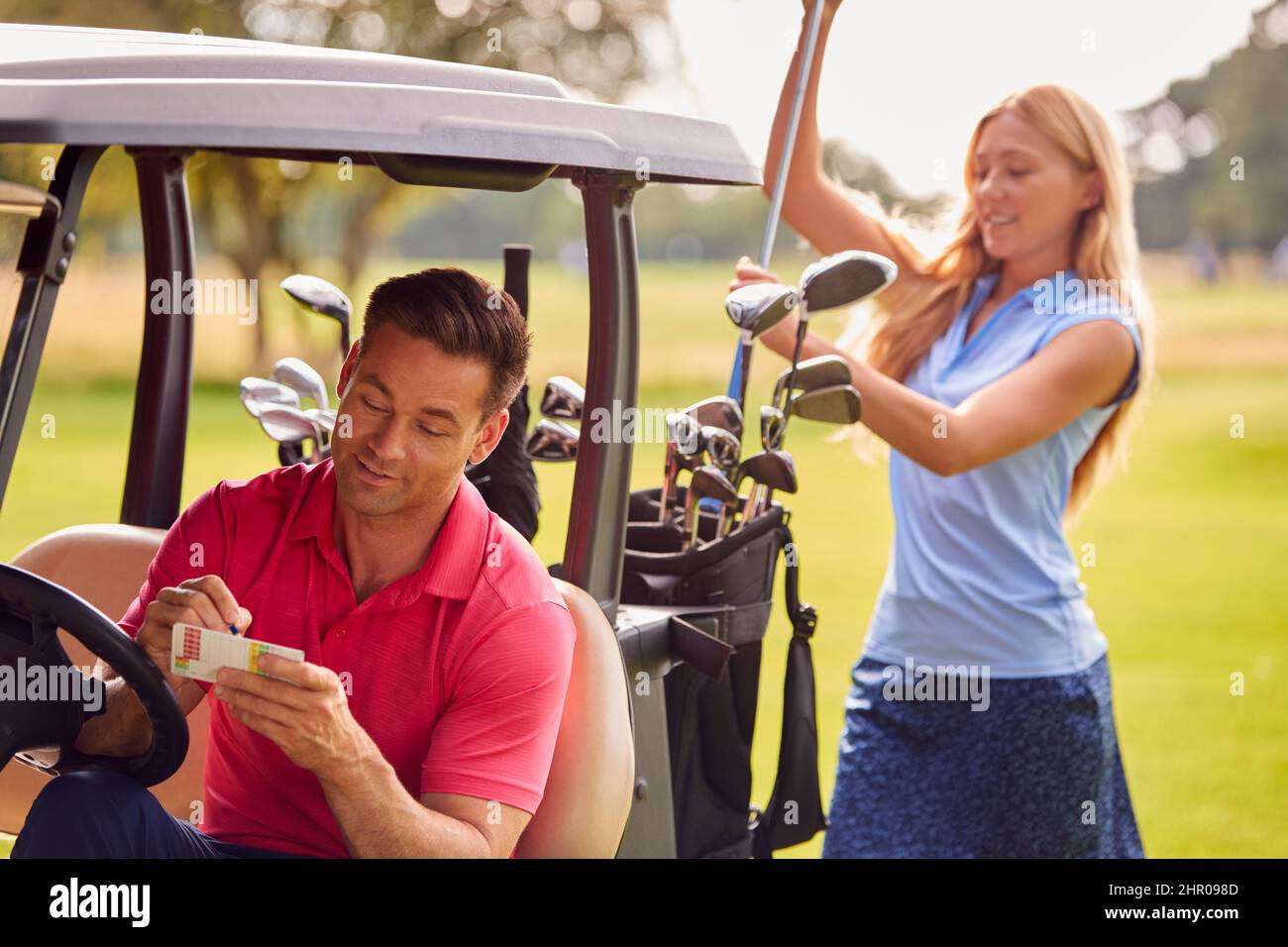 Couple Playing Round On Golf Together Sitting In Buggy With Score Card ...