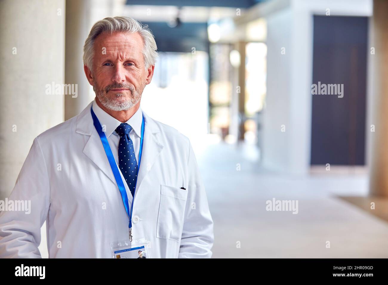 Portrait Of Smiling Mature Doctor Wearing White Coat Standing Inside ...