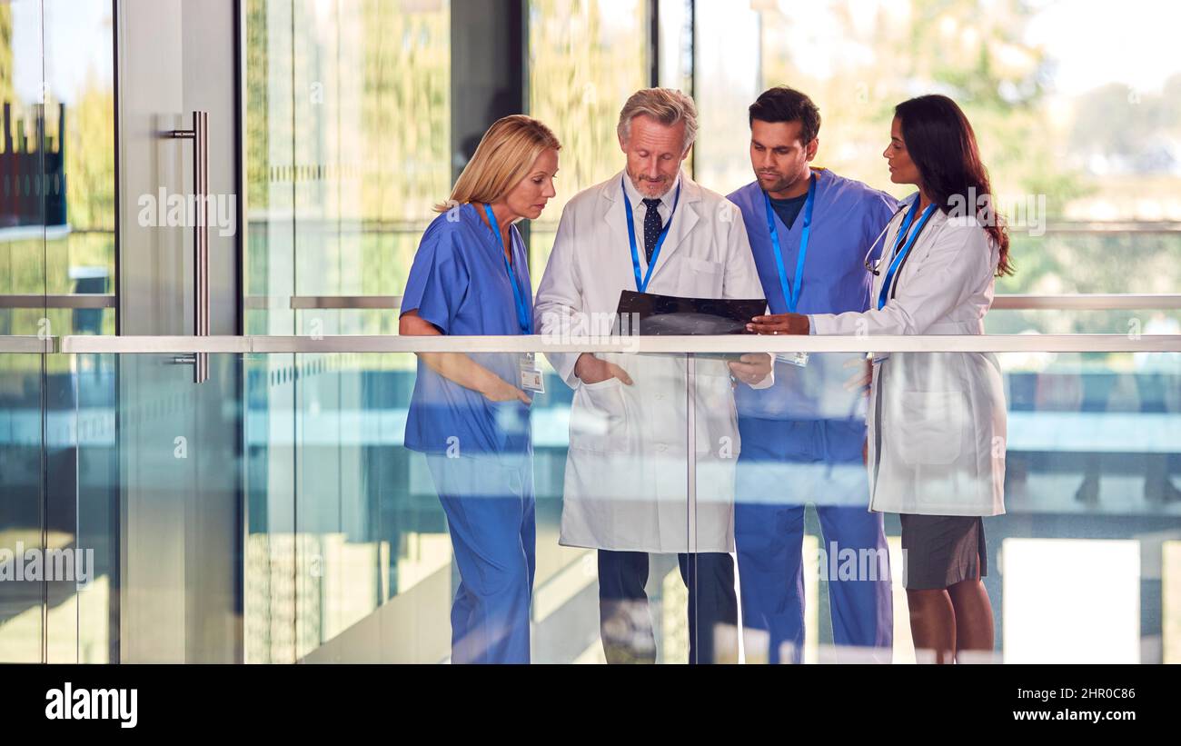 Multi-Cultural Medical Team Wearing White Coats And Scrubs Discuss ...