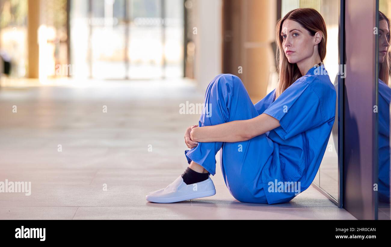 Tired And Overworked Medical Worker In Scrubs Sitting On Floor Of ...