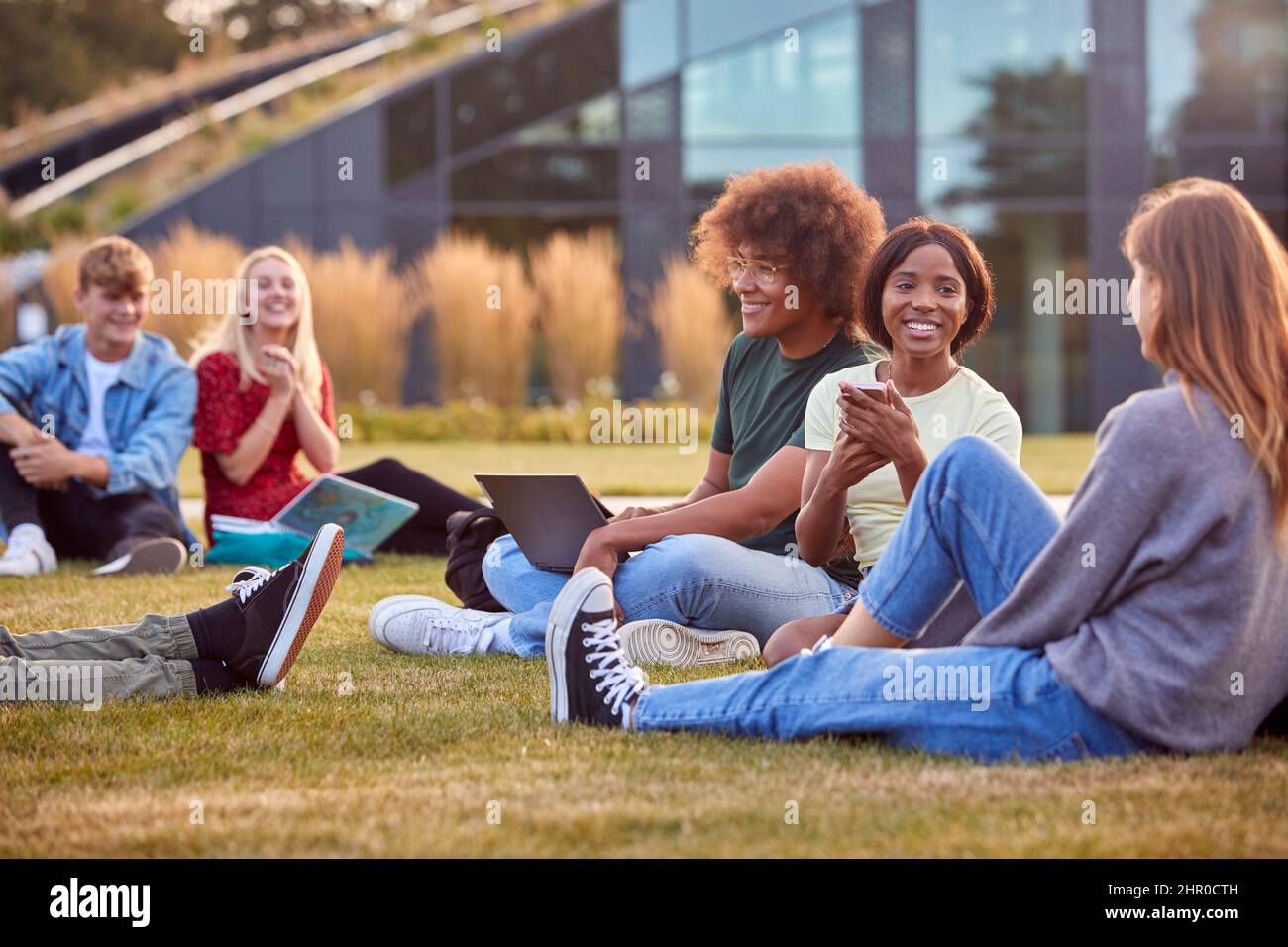 Group Of University Or College Students Sit On Grass Outdoors On Campus ...