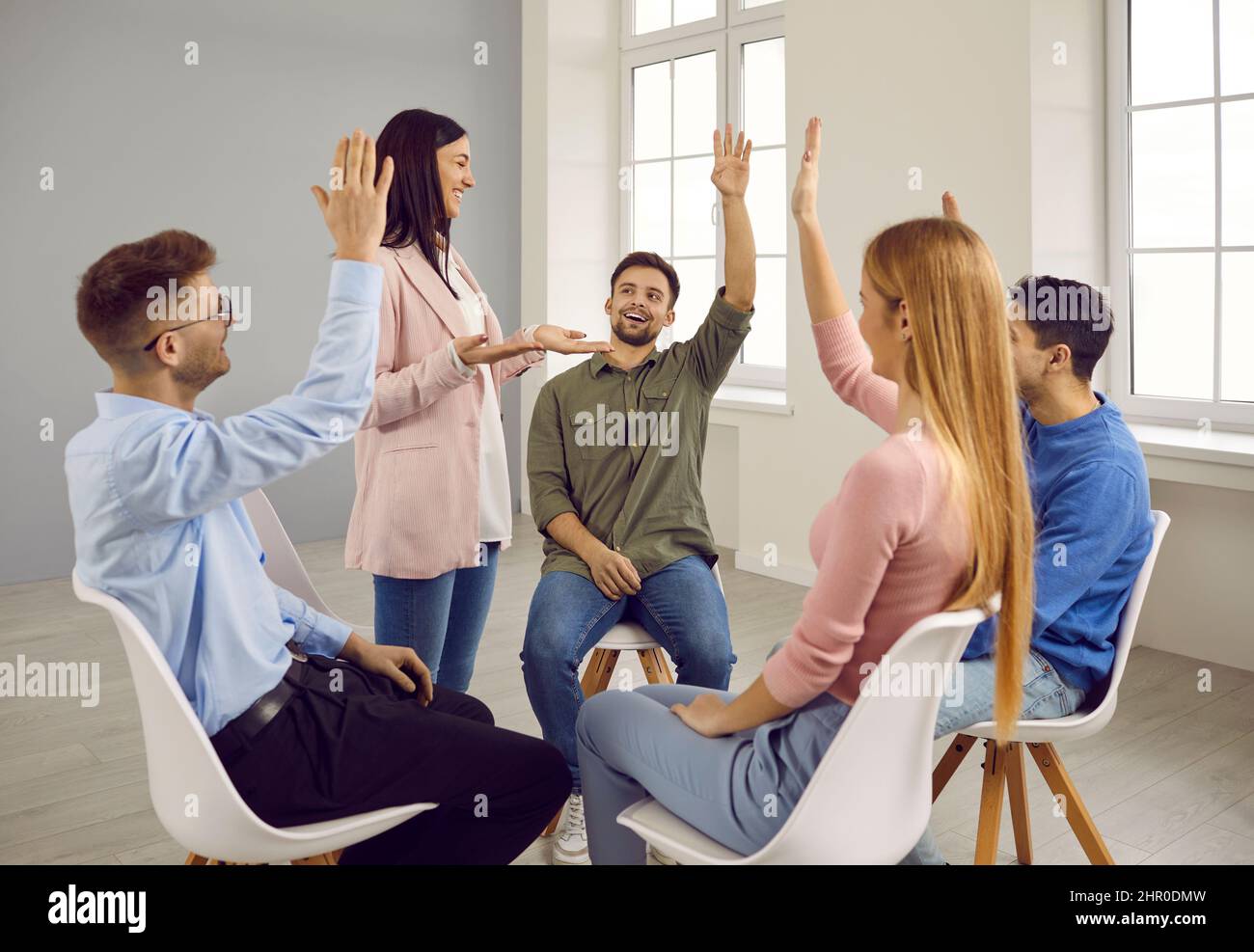 Young people sitting on chairs in circle having fun talking during ...