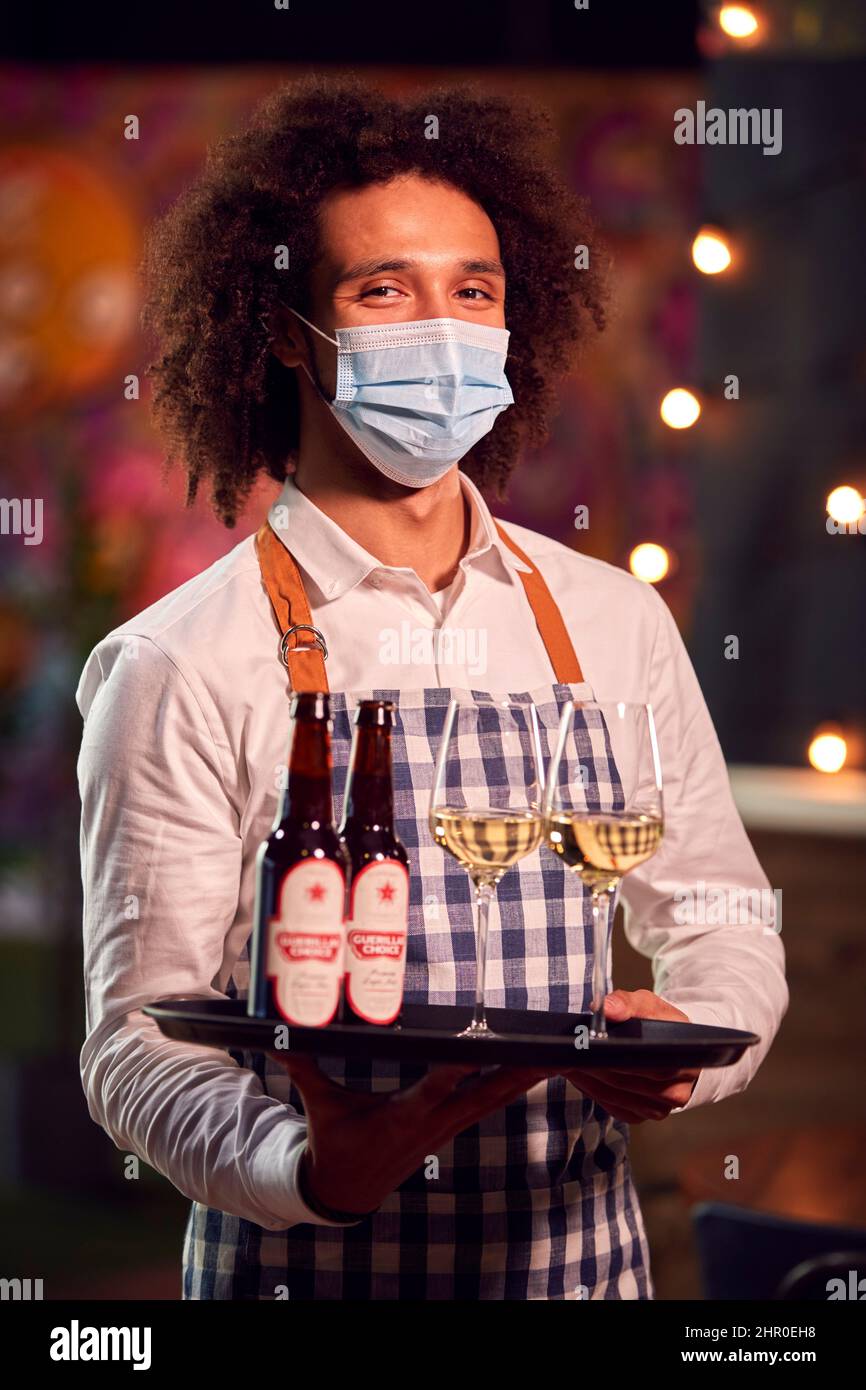 Portrait Of Male Server Wearing Face Mask Holding Tray Of Drinks In ...