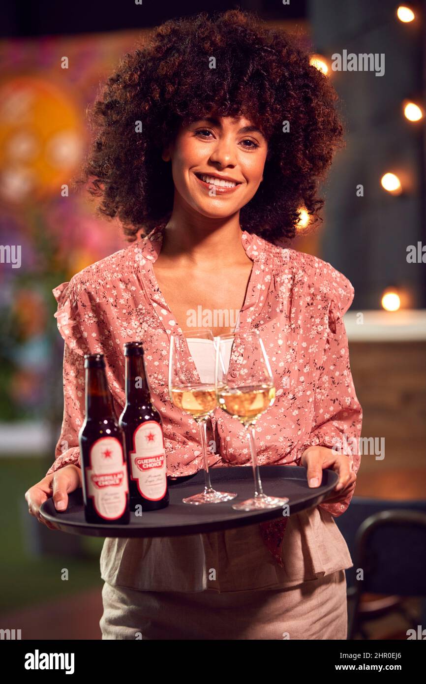 Portrait Of Smiling Female Server Holding Tray Of Drinks In Cool Bar Or ...