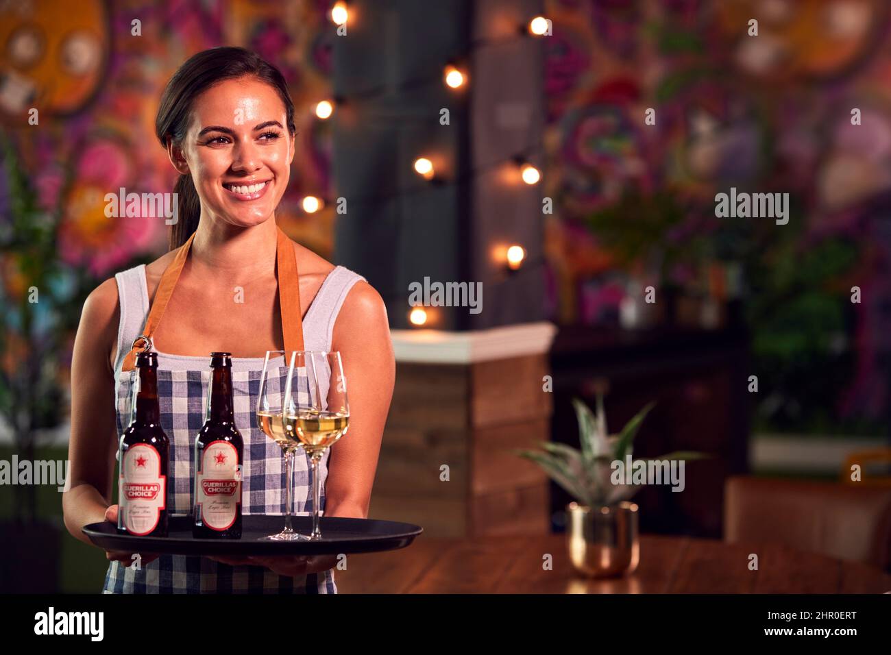Portrait Of Smiling Female Server Holding Tray Of Drinks In Cool Bar Or ...