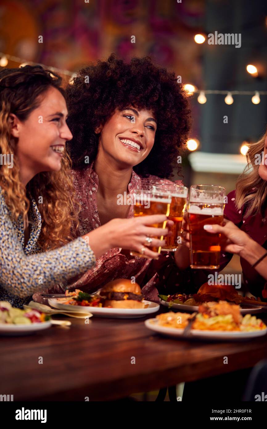 Multi-Cultural Group Of Female Friends Enjoying Night Out Eating Meal ...