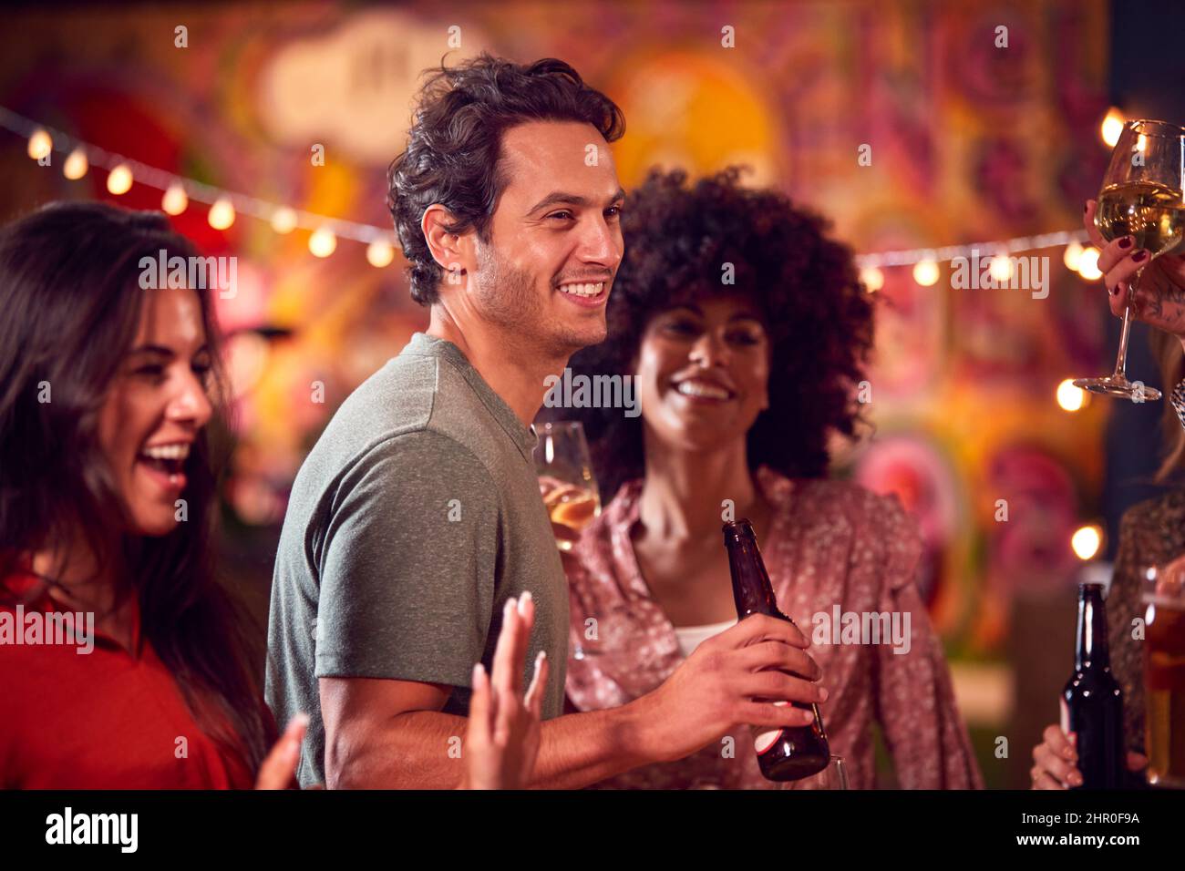 Multi-Cultural Group Of Friends Enjoying Night Out Drinking In Bar ...